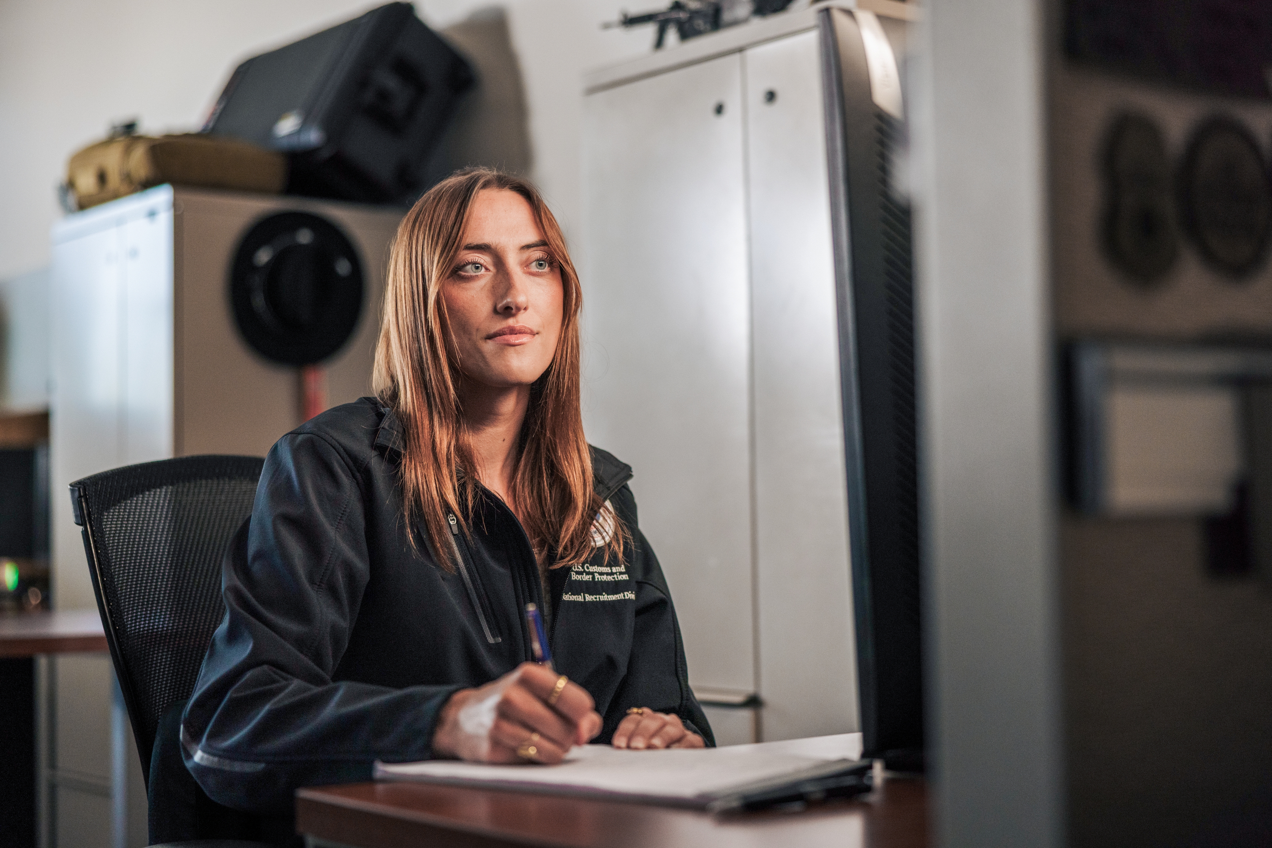 Female officer seated at a desk and taking notes.